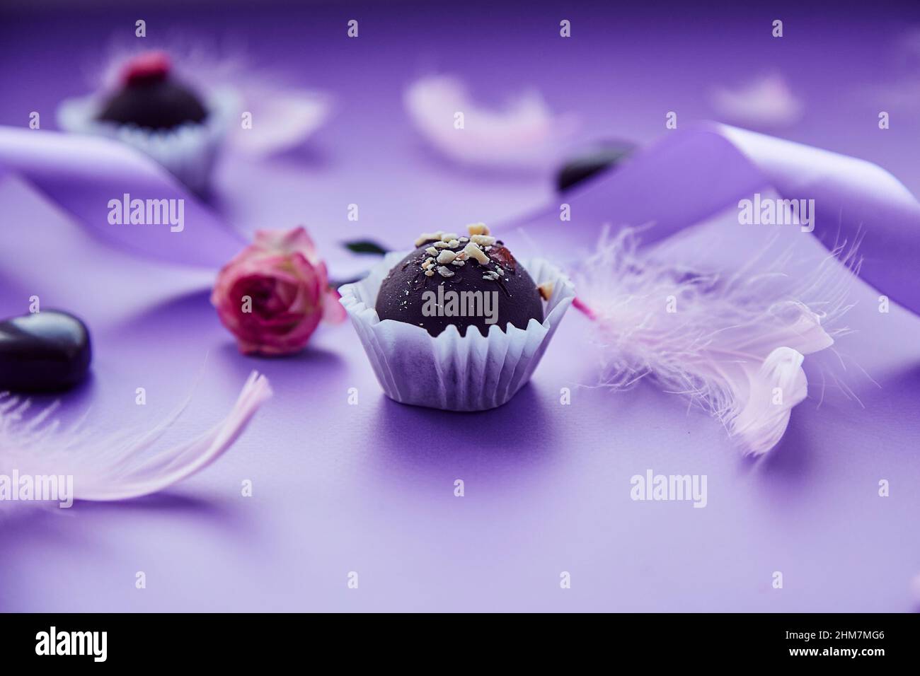 Chocolate festive candy with nuts and pink rose. Trendy pink feathers ...