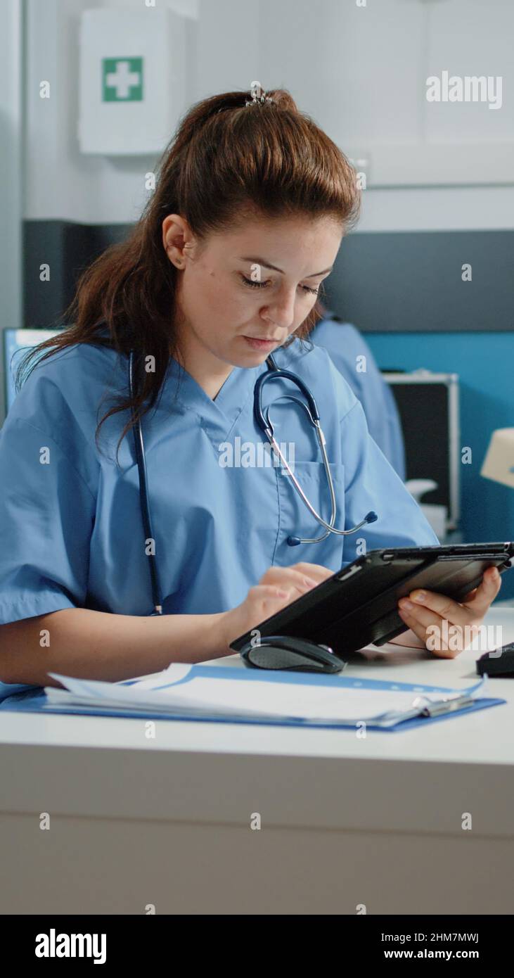 Medical assistant typing on tablet screen and checking computer for ...