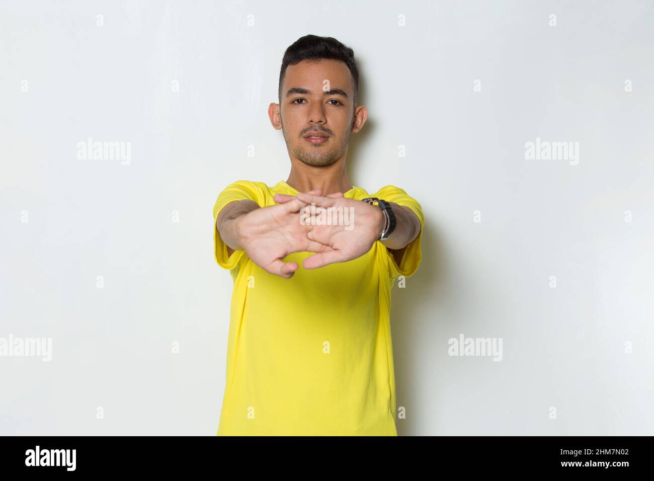 young sporty man dressed in yellow tshirt doing stretching on white ...