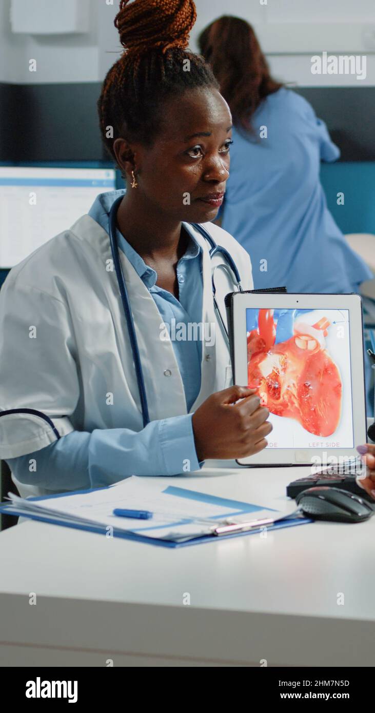 Doctor showing tablet with heart figure for cardiology checkup to ...