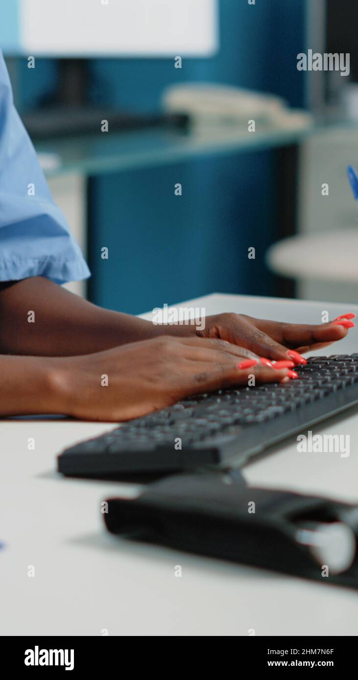 Close up of medical assistant typing on computer keyboard in cabinet ...