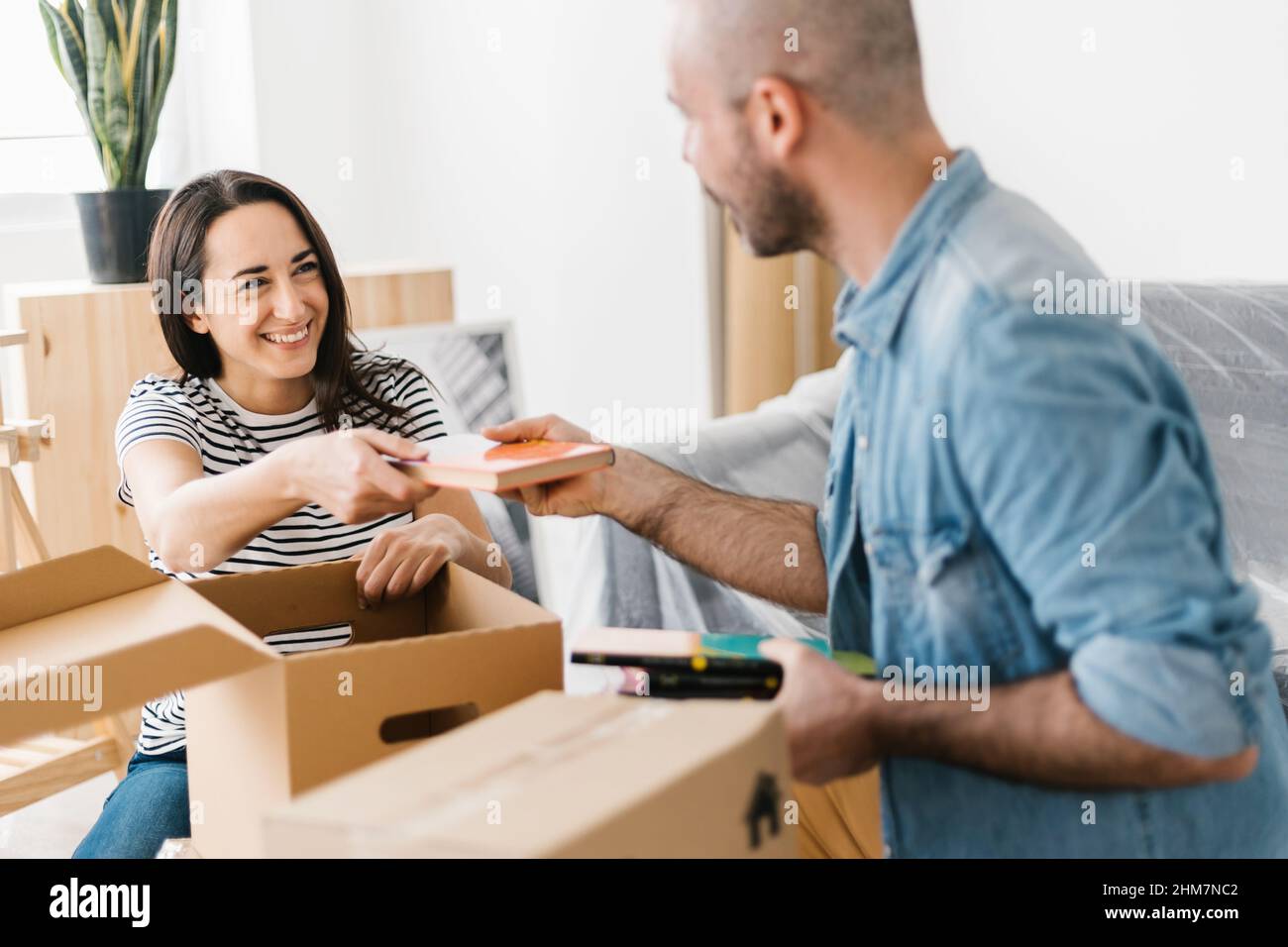 Happy Young Couple Unpacking Cardboard Boxes While Moving To New