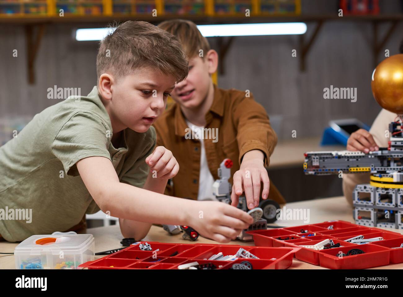 Portrait of two young boys building robots while enjoying engineering ...