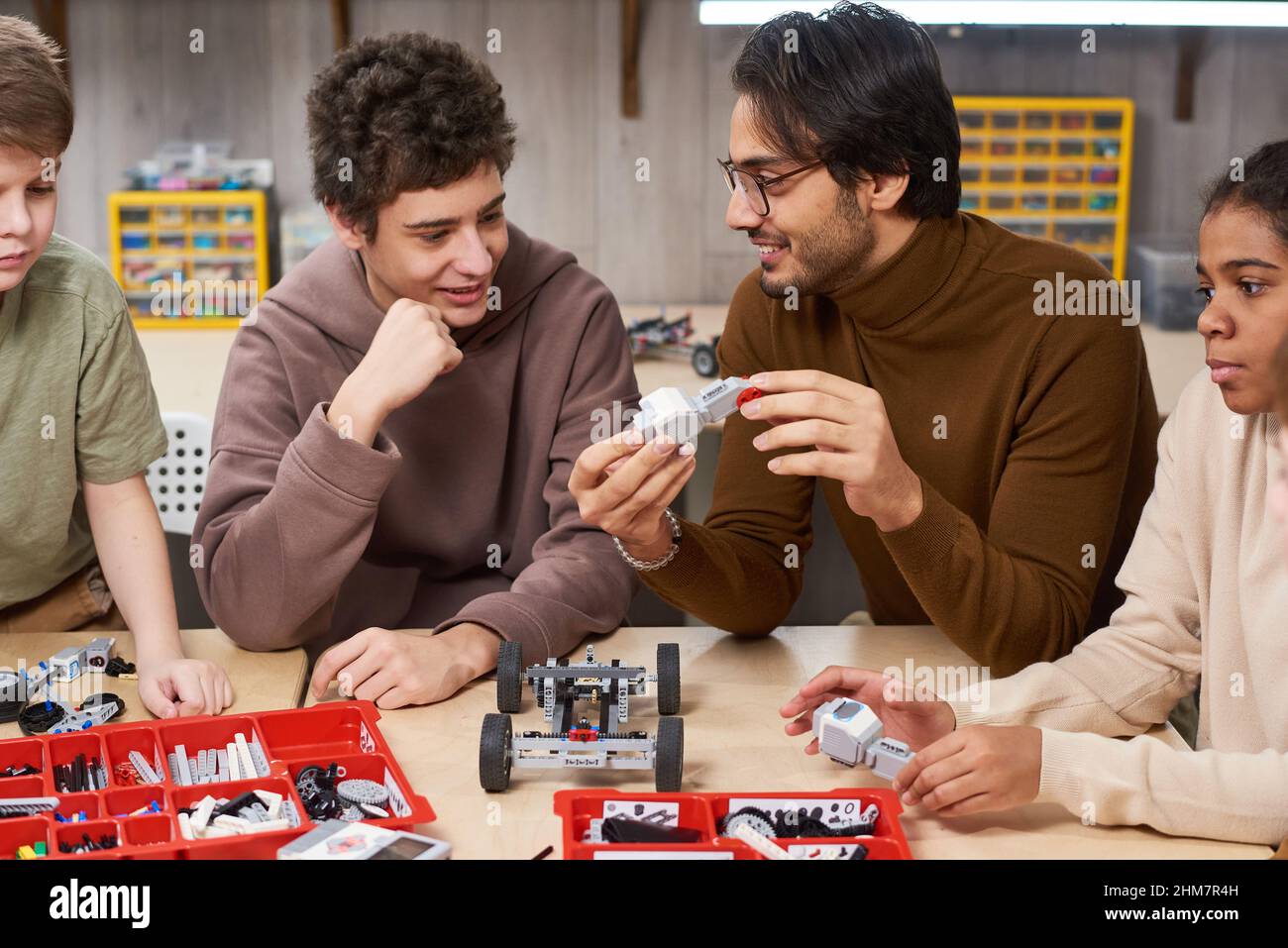 Portrait of smiling male teacher helping diverse group of children ...