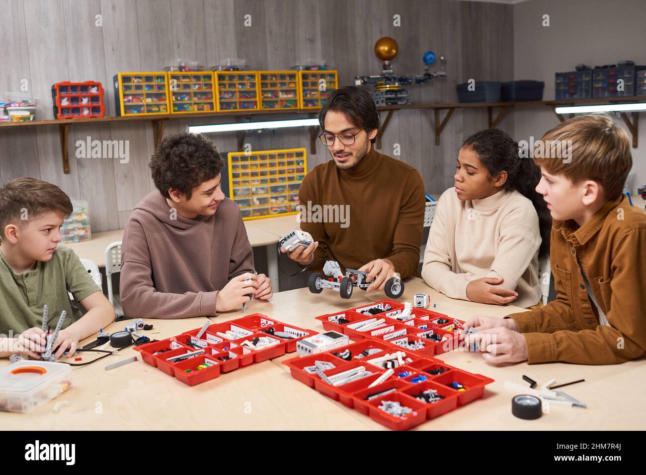 Portrait of smiling male teacher helping diverse group of teenage kids ...