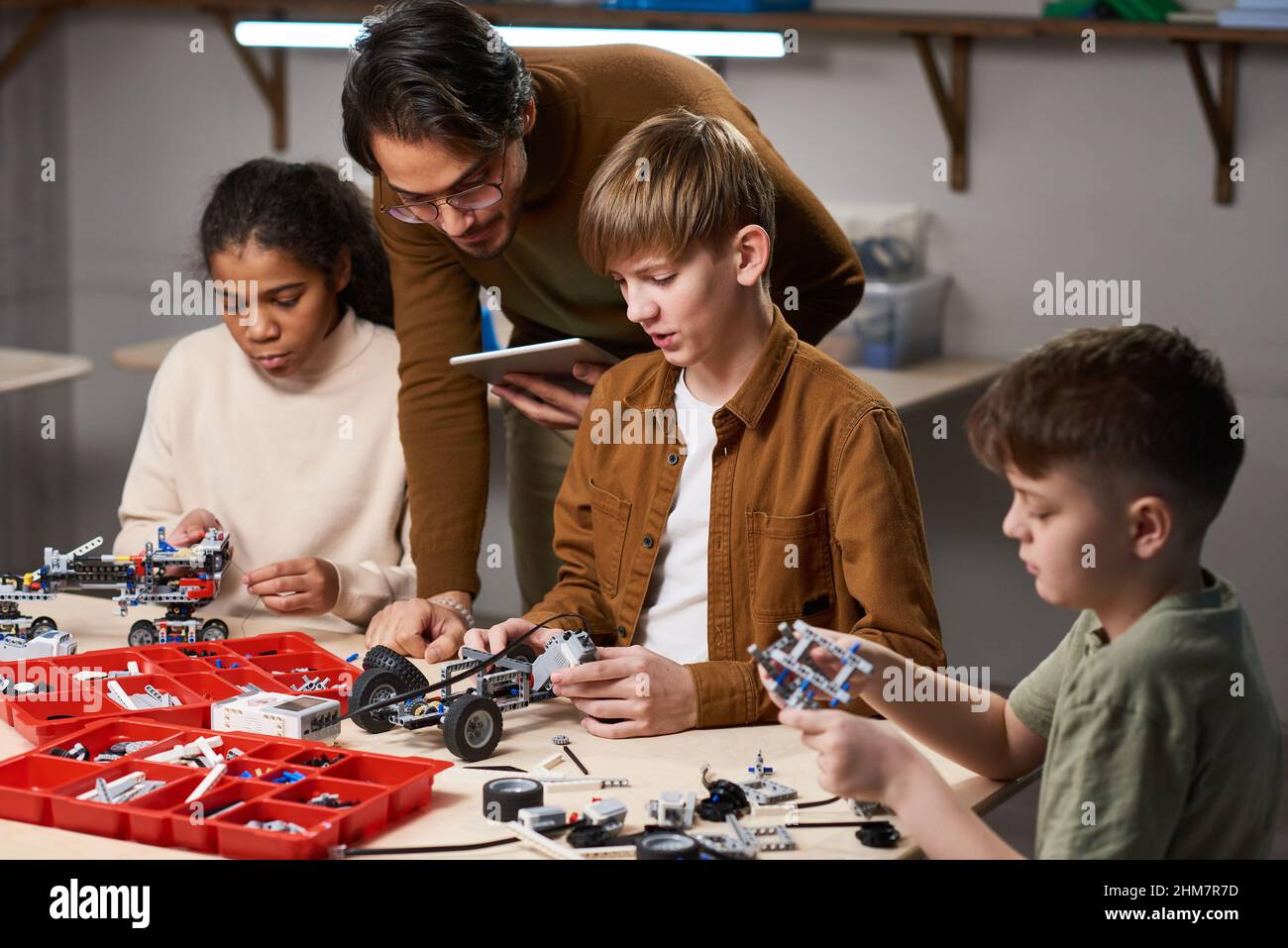 Portrait of blonde young boy building robot with diverse group of ...