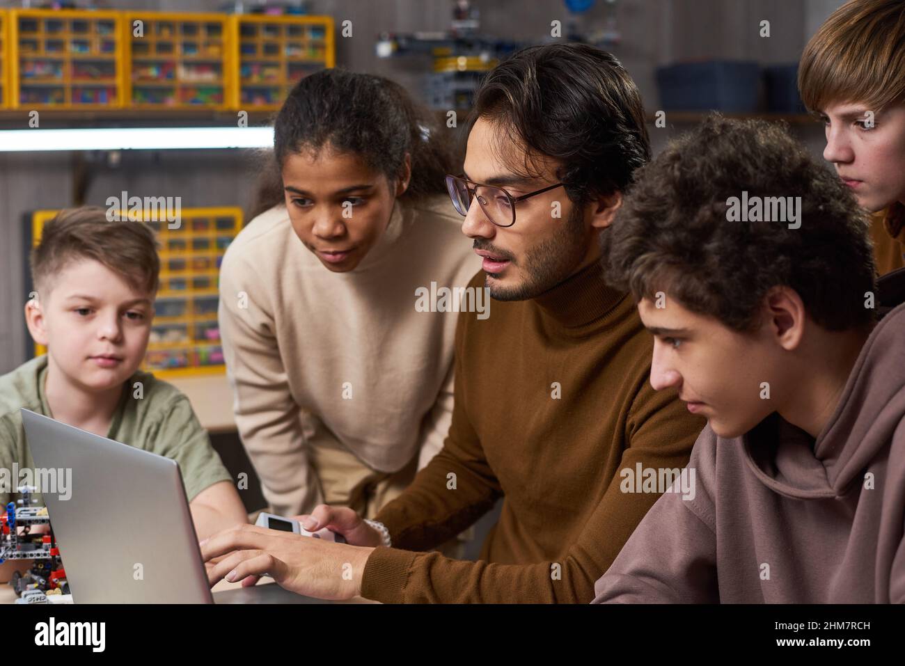 Side view portrait of young male teacher using laptop with diverse ...