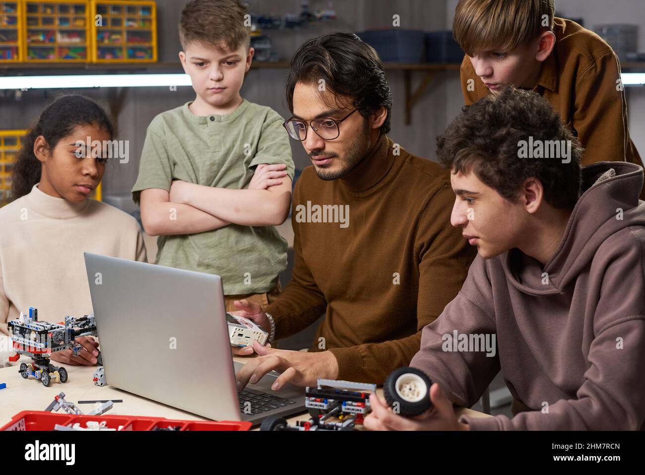 Portrait of young male teacher with diverse group of children using ...