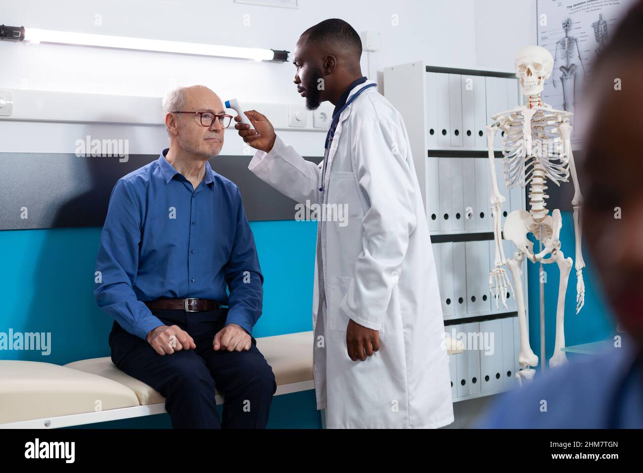 African american practitioner doctor putting infrared thermometer on ...