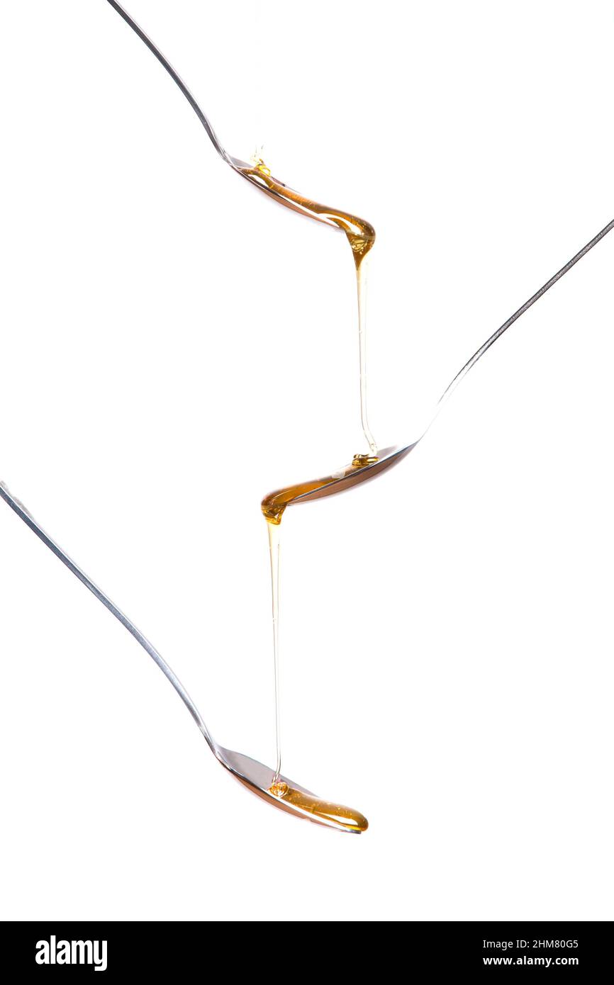 Spoons of honey dripping on one another Stock Photo - Alamy