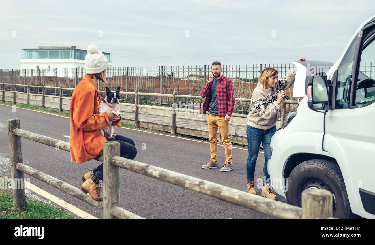 Female mechanic fixing the broken down camper van of a couple going on ...