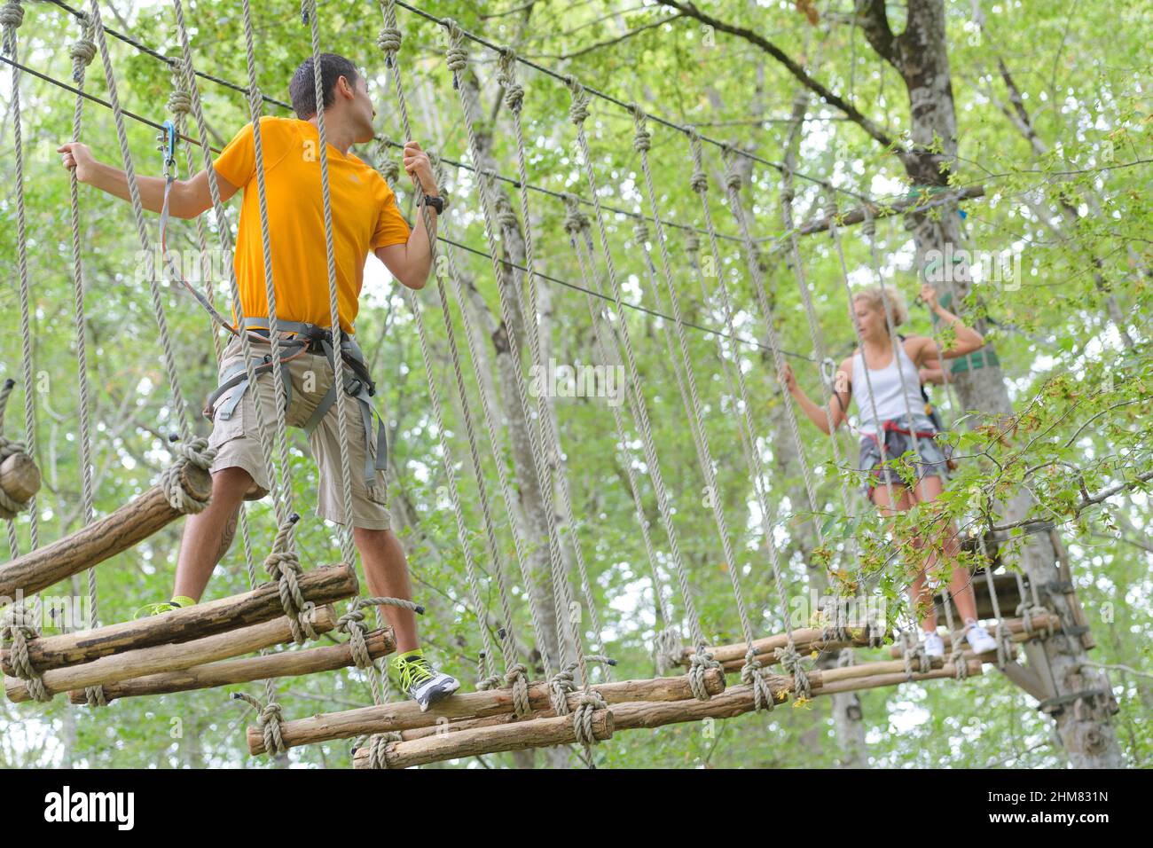 young adults having fun crossing a rope bridge Stock Photo - Alamy