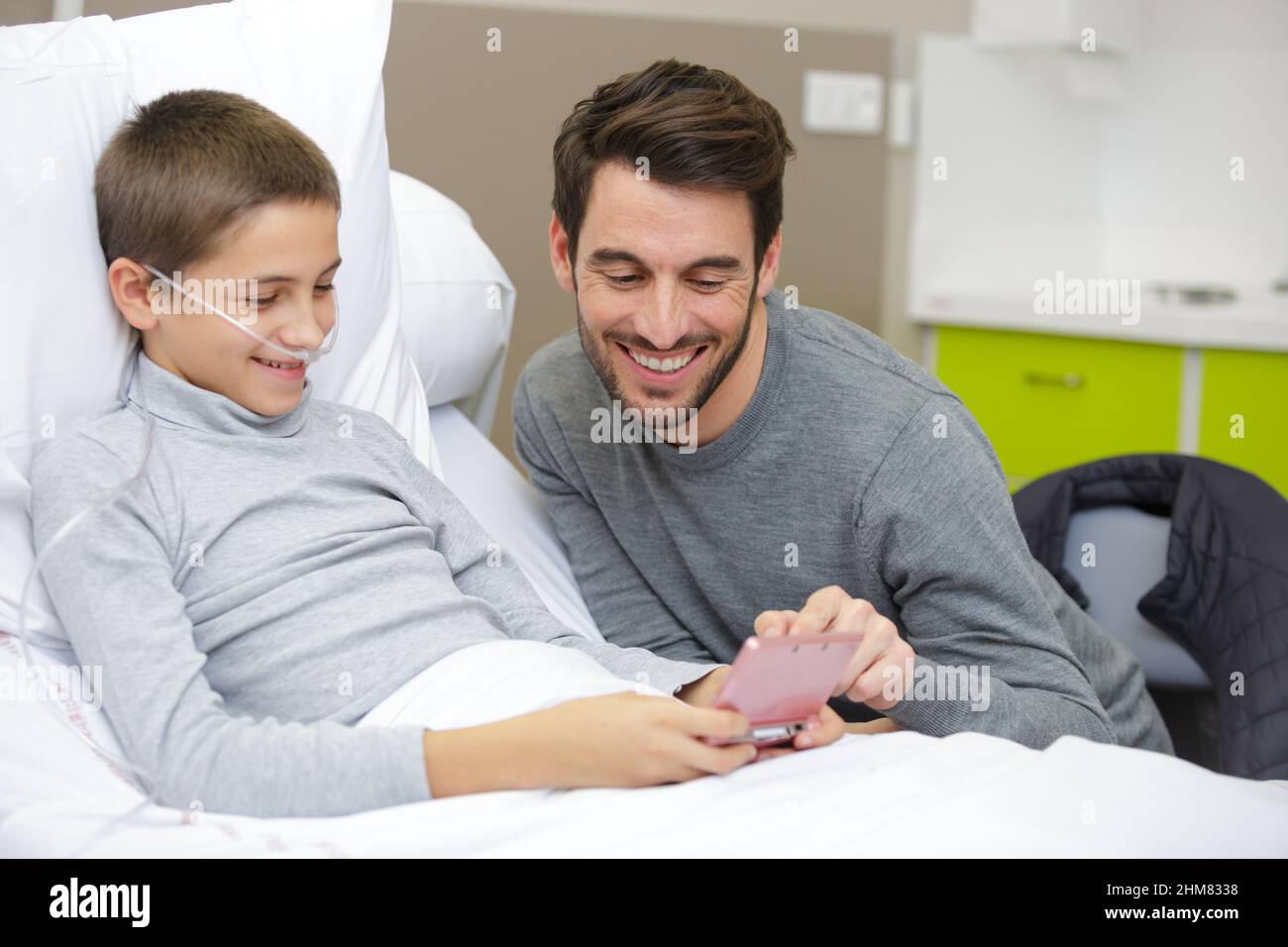 dad sitting near sick son in hospital bed Stock Photo - Alamy