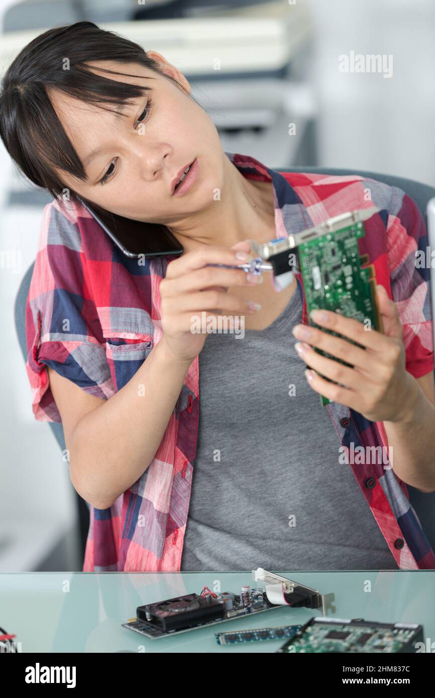 handywoman checking computer motherboard while speaking on the phone ...