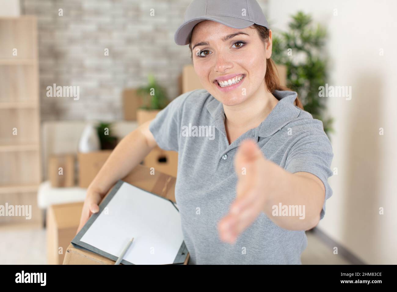 young woman holding box giving hand for a handshake Stock Photo - Alamy