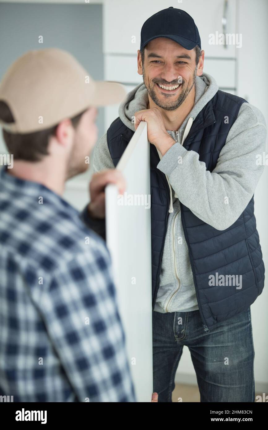 two men carrying plasterboard sheet Stock Photo - Alamy