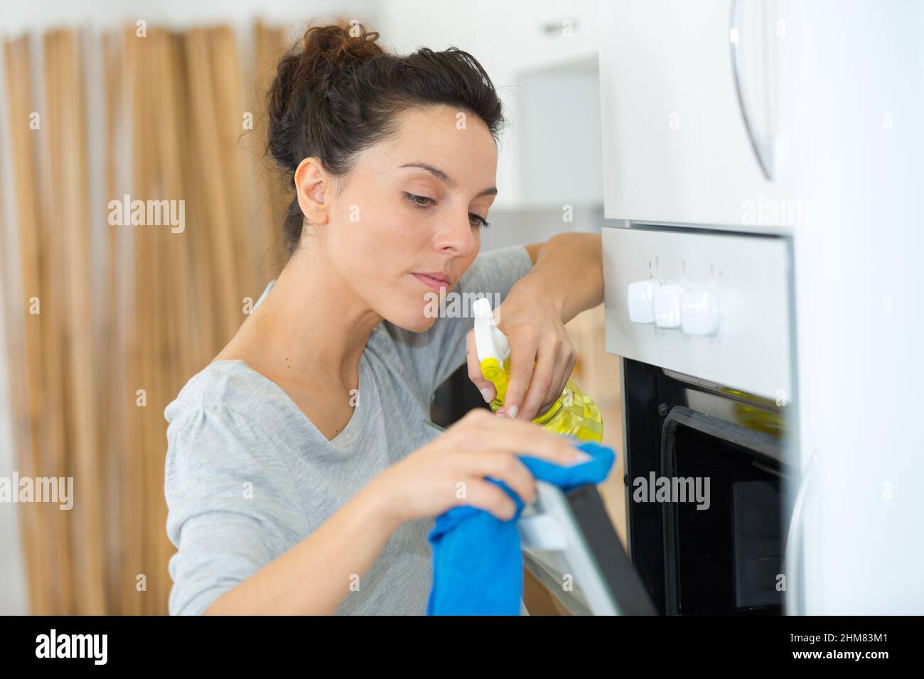 pretty woman cleaning oven with rag Stock Photo - Alamy