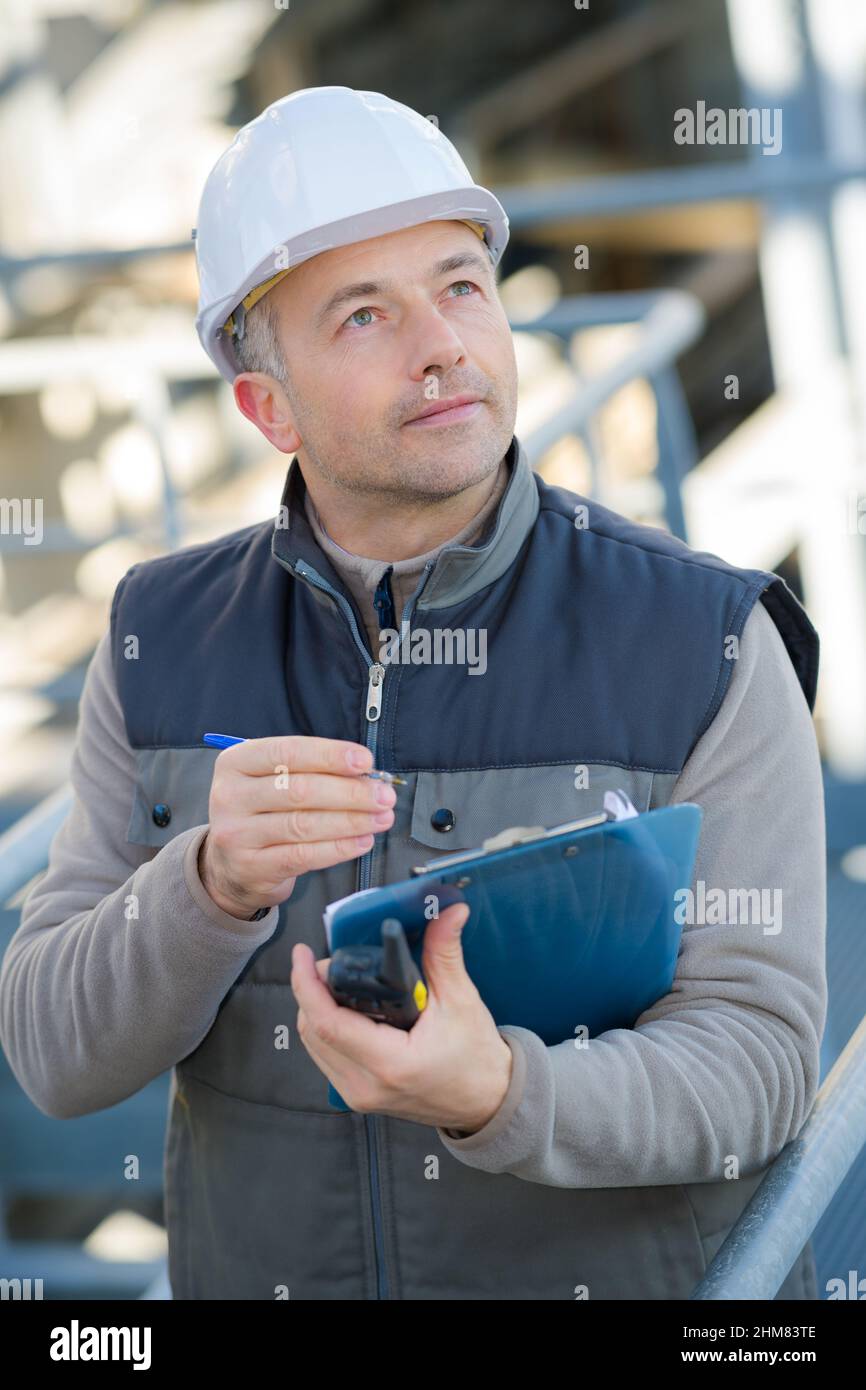 contented male worker on industrial work site holding clipboard Stock ...