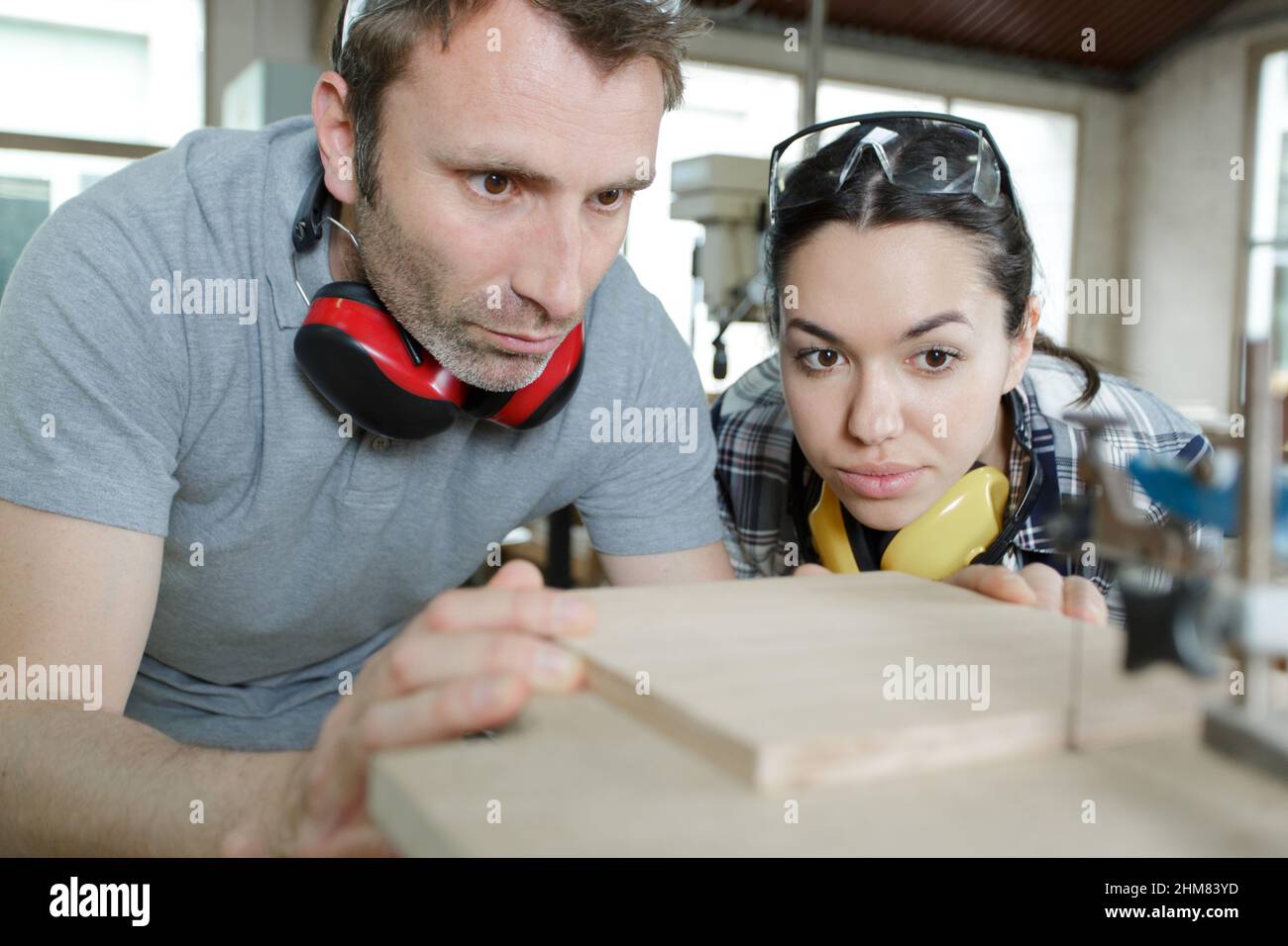 man explaining woman how to cut wood Stock Photo - Alamy