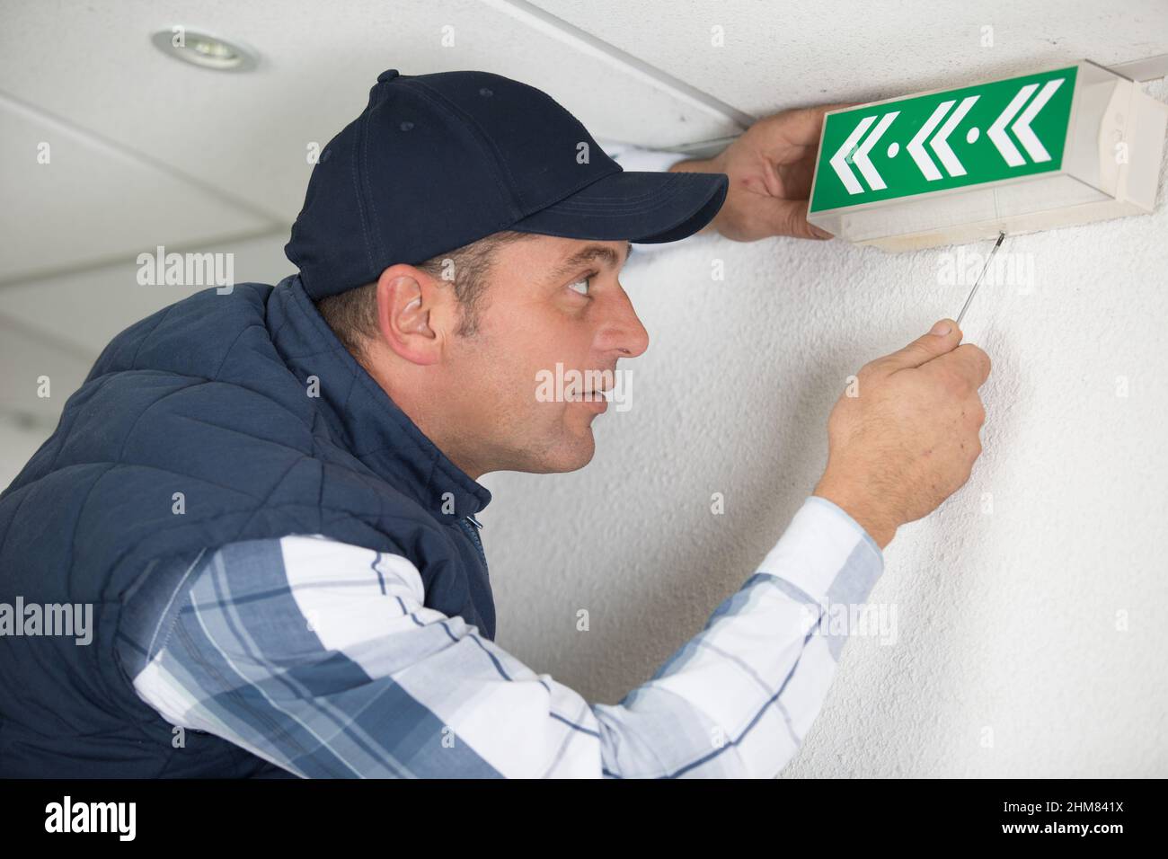 a male worker fixing an emergency exit sign Stock Photo - Alamy