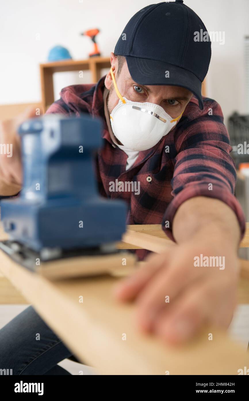 carpenter sanding a wood with sander in carpentry workshop Stock Photo ...