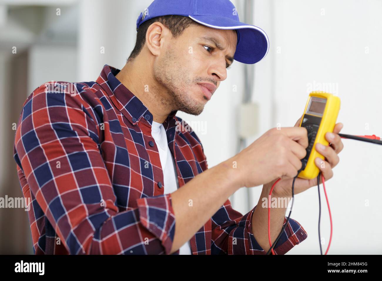 smiling electrician using multimeter on electric meter Stock Photo - Alamy