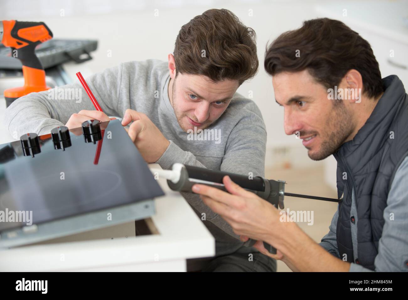 two men installing a kitchen hob Stock Photo - Alamy