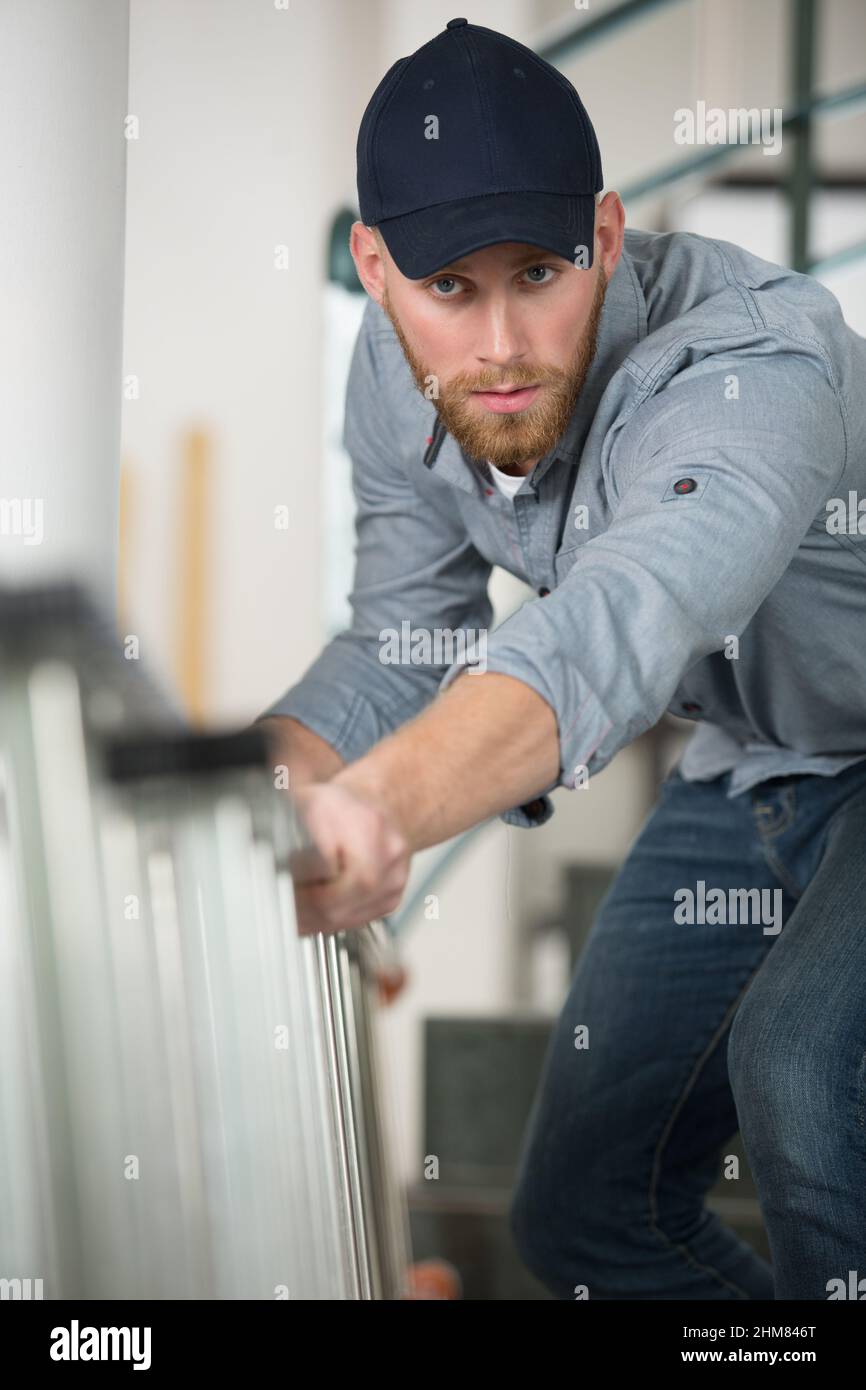a serious young man carrying a ladder Stock Photo - Alamy