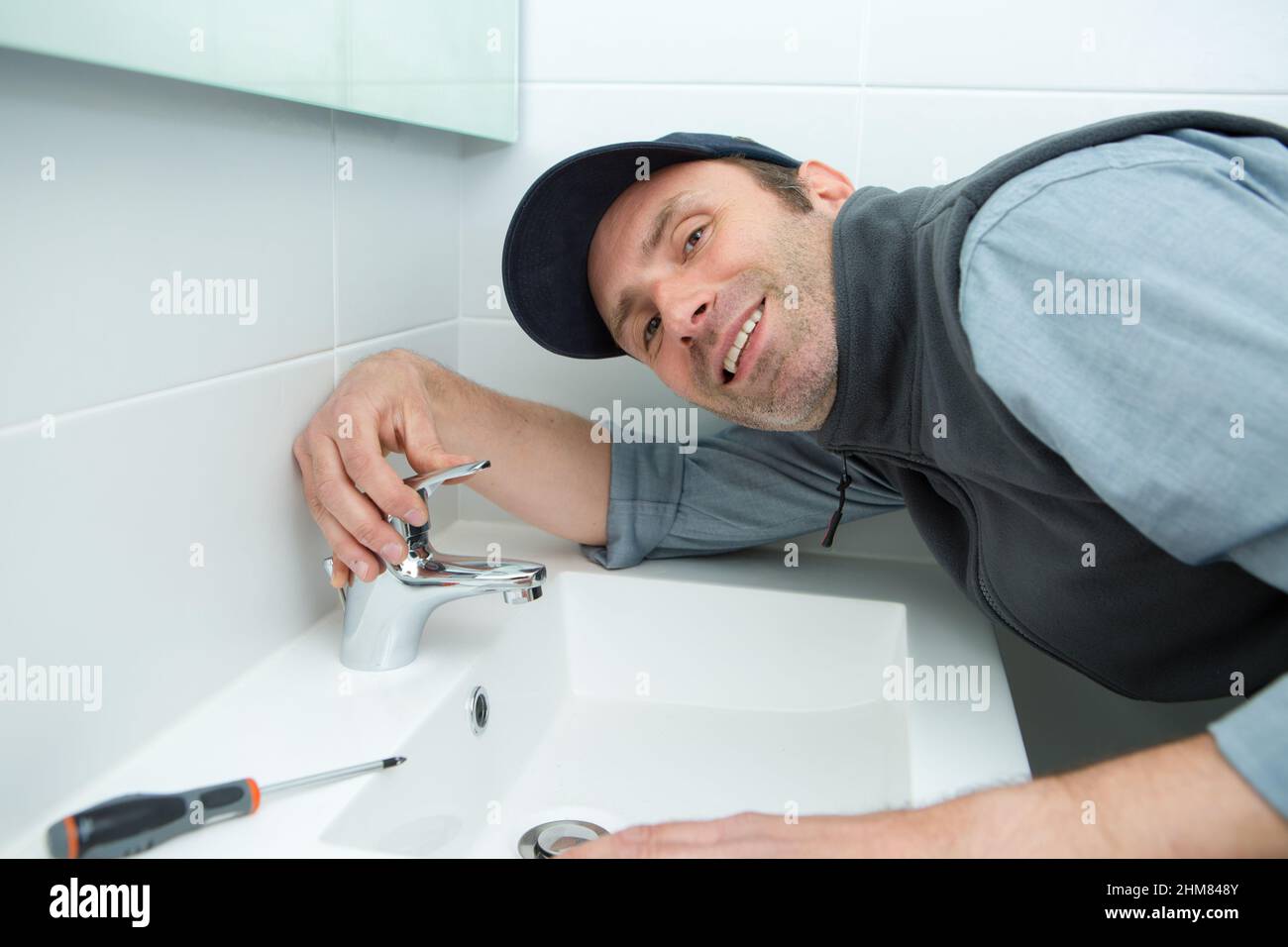 happy man fixing tap with wrench in the kitchen Stock Photo - Alamy