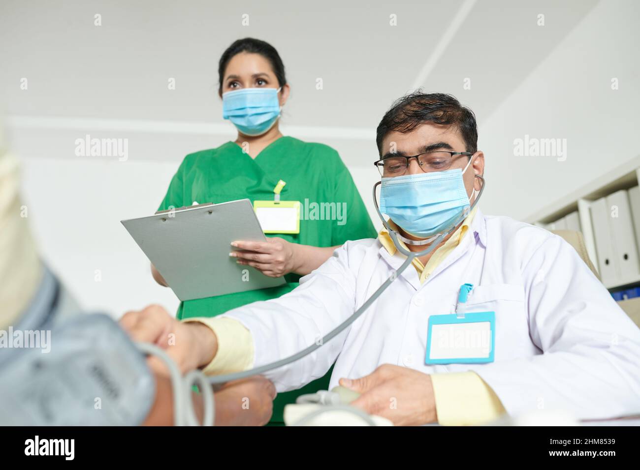 General practitioner checking blood pressure of patient when medical ...