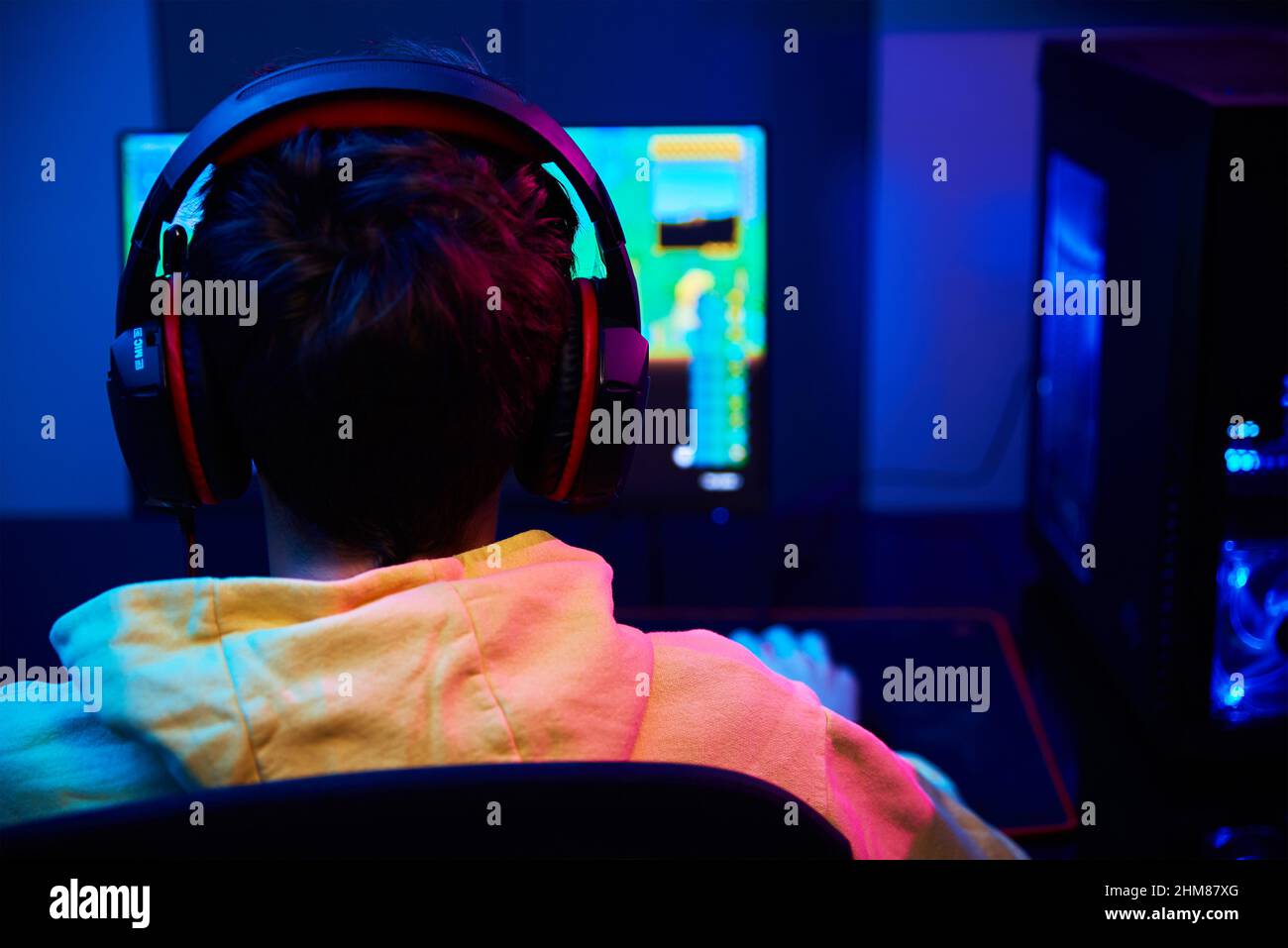 Teenager boy play computer video game in dark room, use neon colored ...