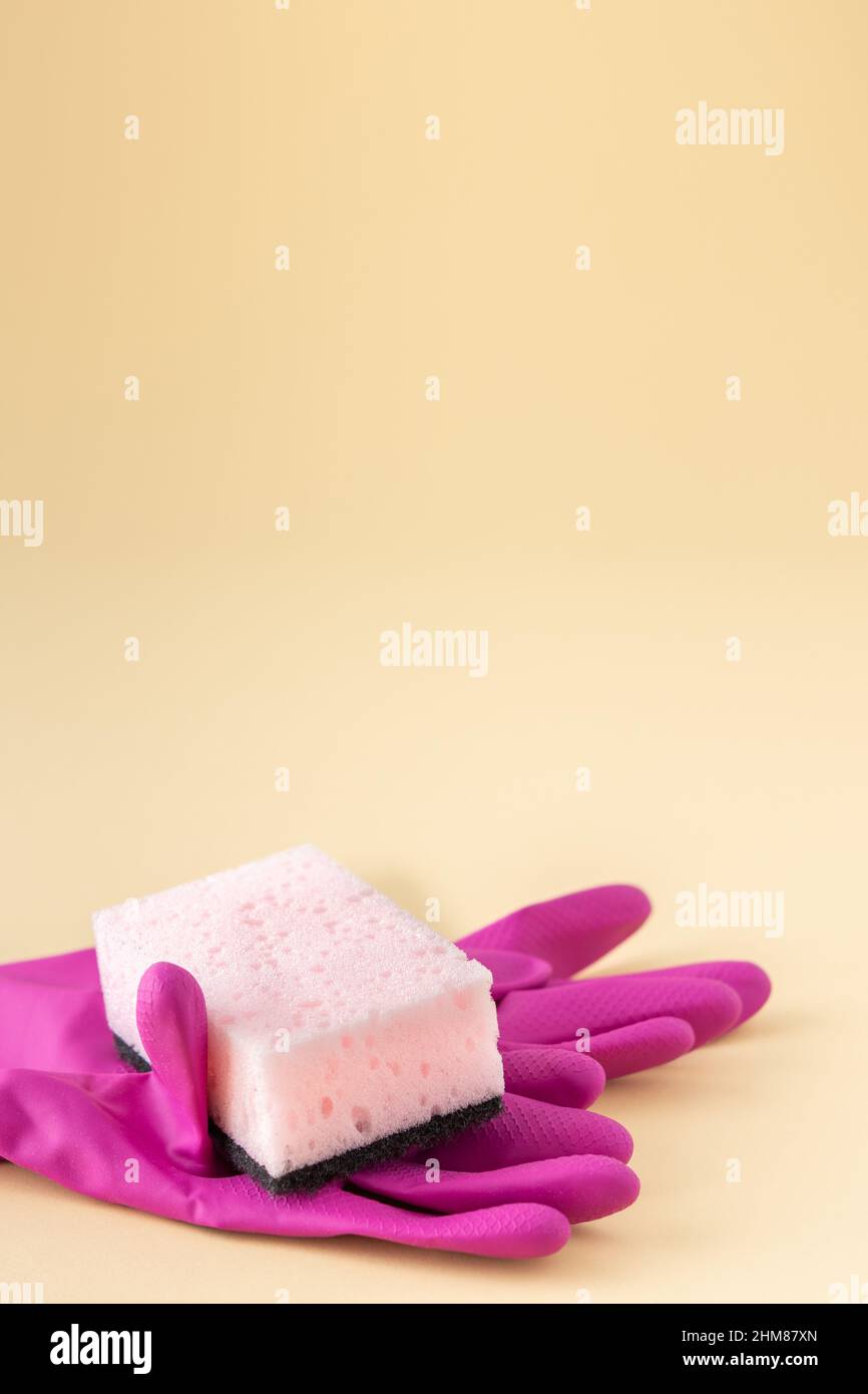 Pink dishwashing sponge and rubber gloves on neutral beige background ...
