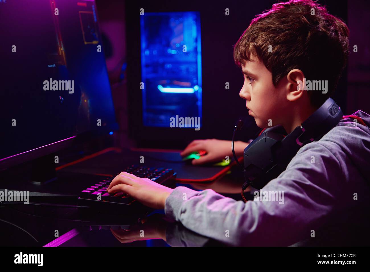 Teenager boy play computer video game in dark room, use neon colored ...
