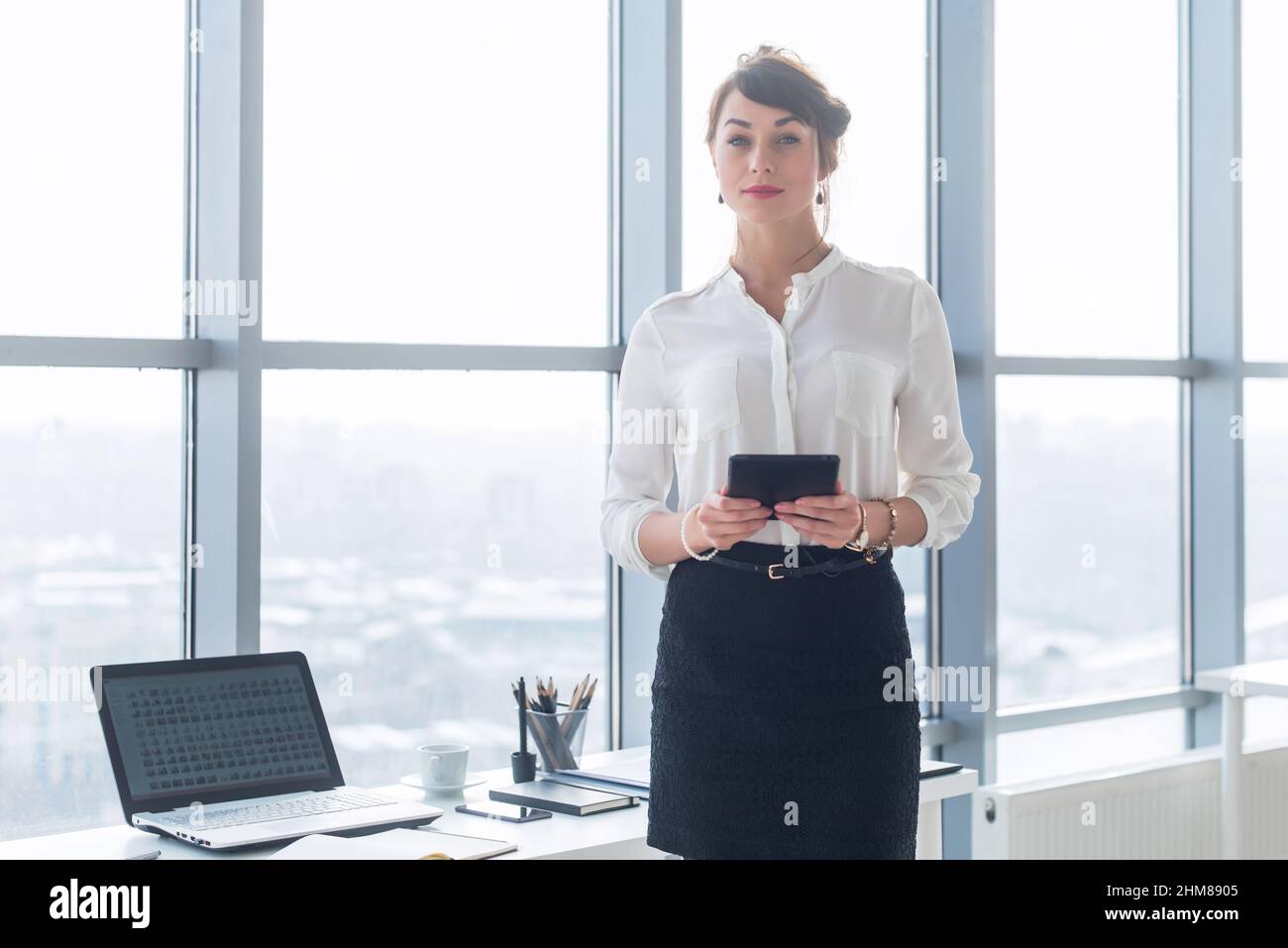 Rear view portrait of a young female office worker using apps at her ...