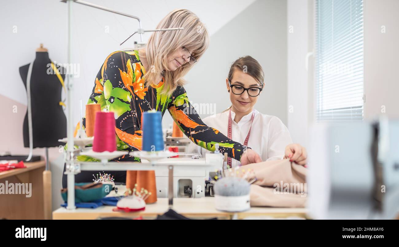 Senior tailor checks the quality of work of the junior female tailor in ...