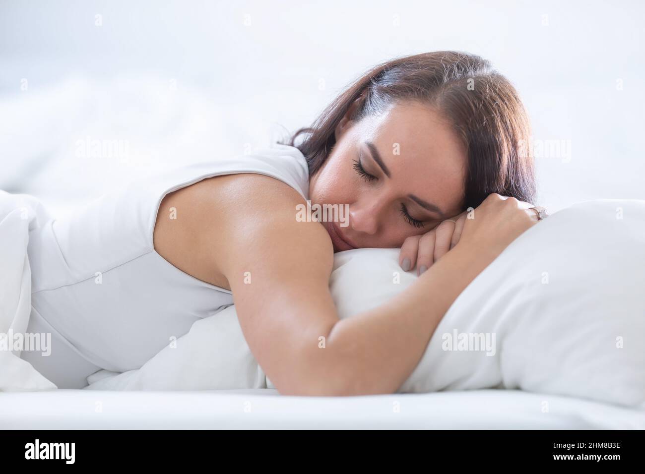 Woman sleeping on her belly in white blankets and white shirt Stock ...