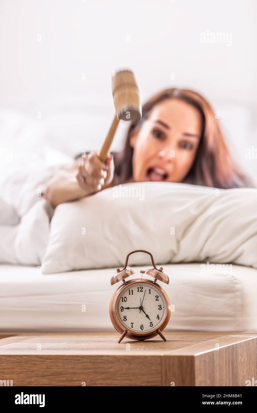 Smashing of alarm clock with the hammer by a woman reaching out from ...