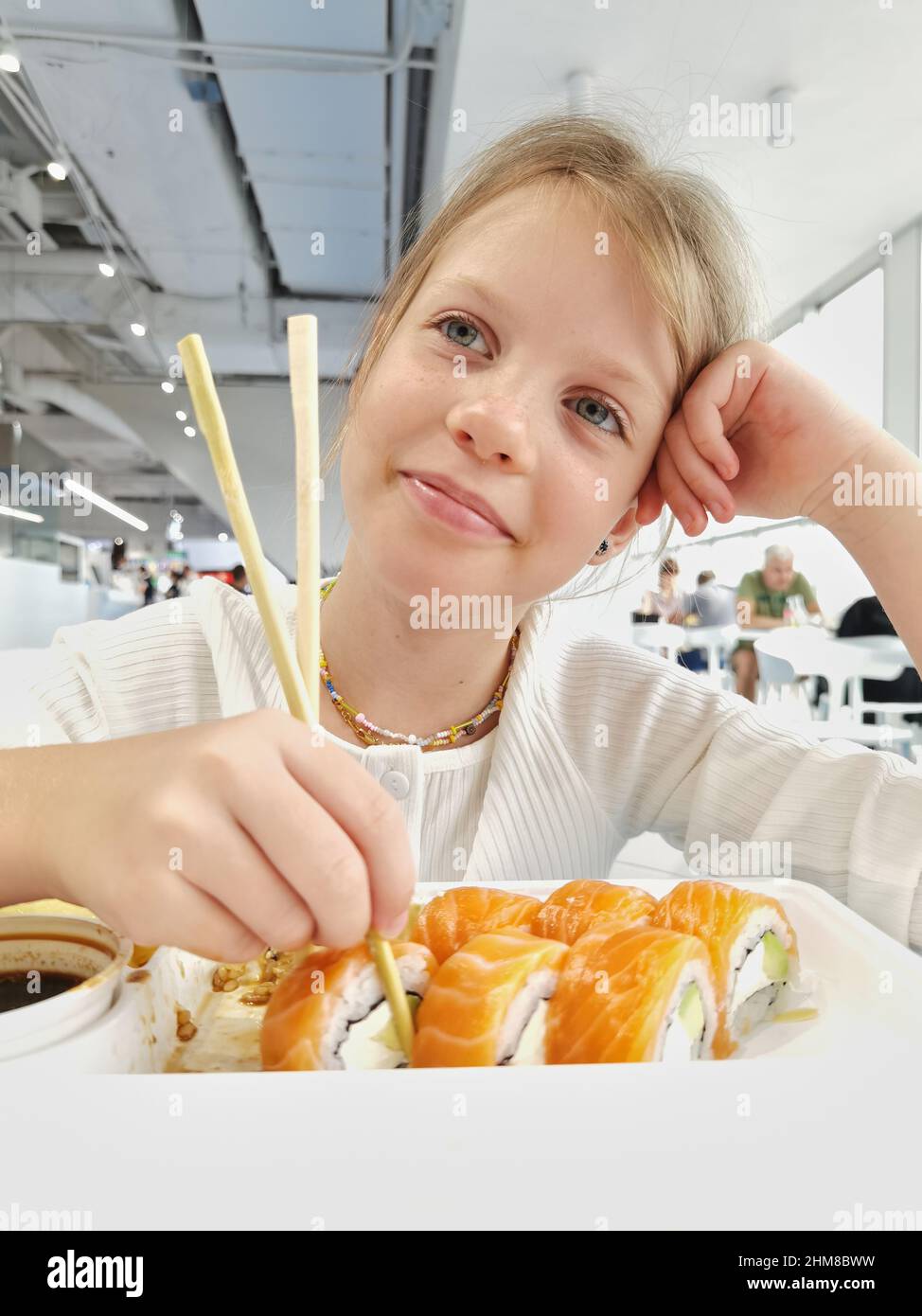 Cute smiling little girl with sushi. Child girl eating sushi and rolls ...