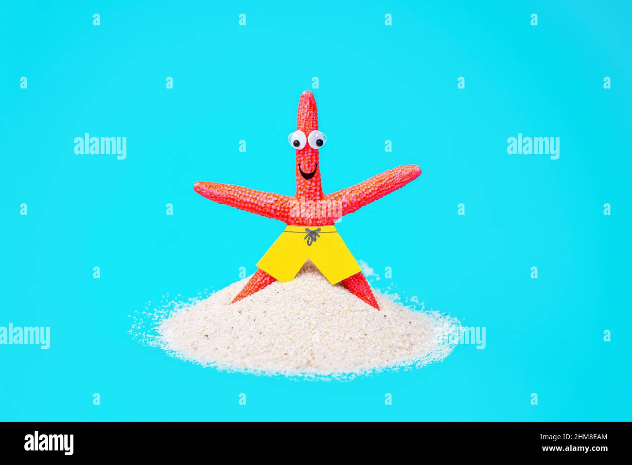 Funny starfish character standing in a pile of sand surrounded by ...