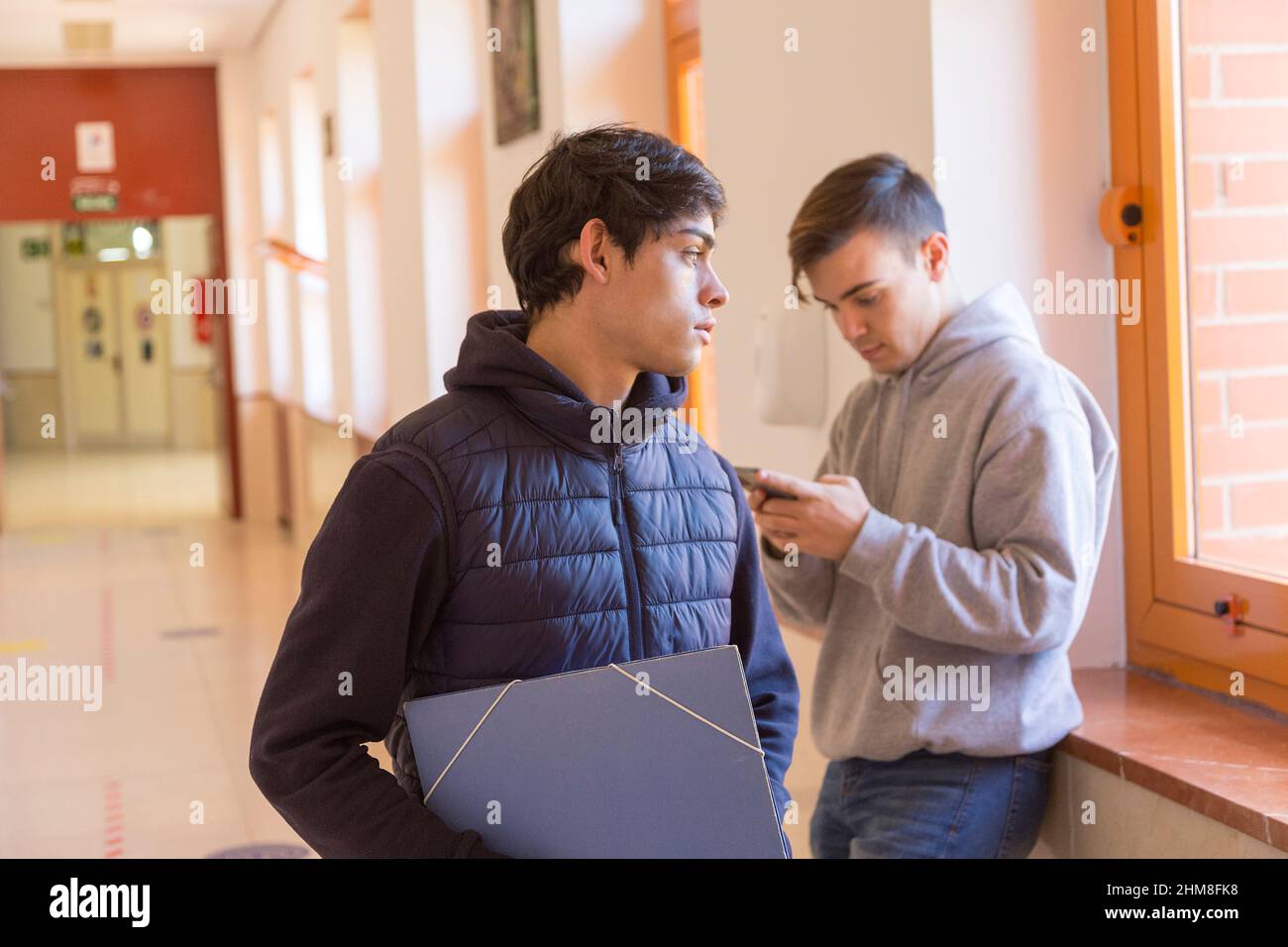 two university students in the corridor of the faculty using mobile ...