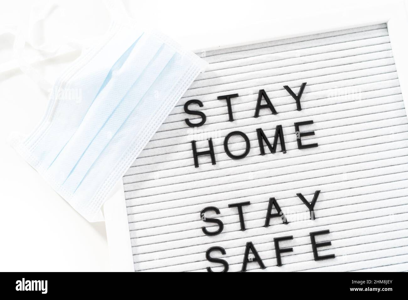 STAY HOME and STAY SAFE sign on message board with a blue medical mask ...
