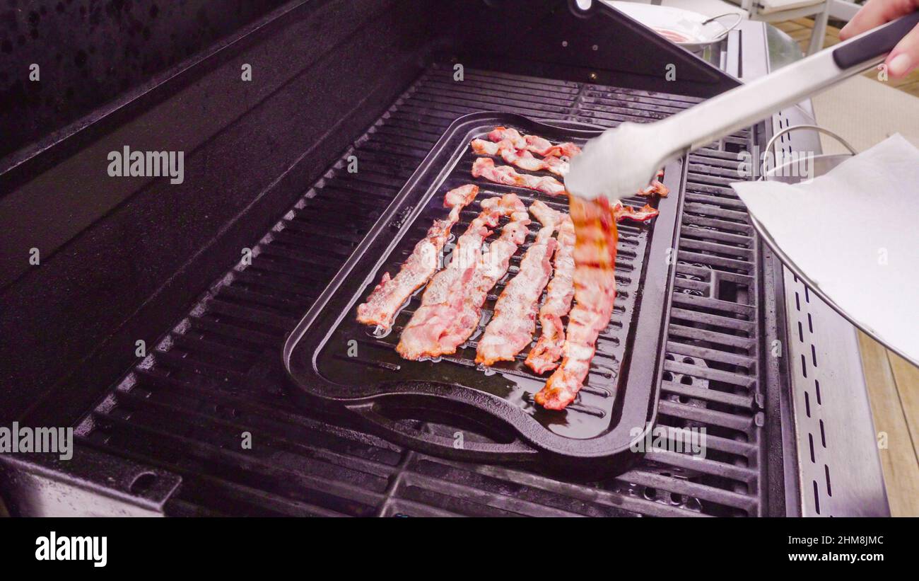Cooking bacon stips on an outdoor gas grill Stock Photo - Alamy