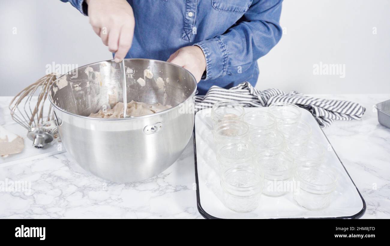Step by step. Scooping homemade chocolate ice cream into glass jars ...