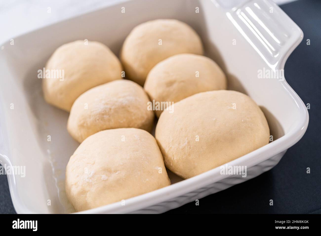 Rising dough in a white ceramic dish to prepare dinner rolls Stock ...