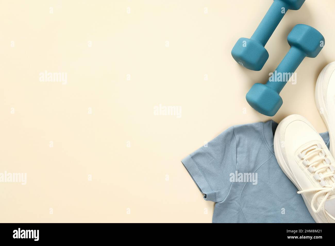 Feminine sports equipment on pastel beige background. Dumbbells, t ...