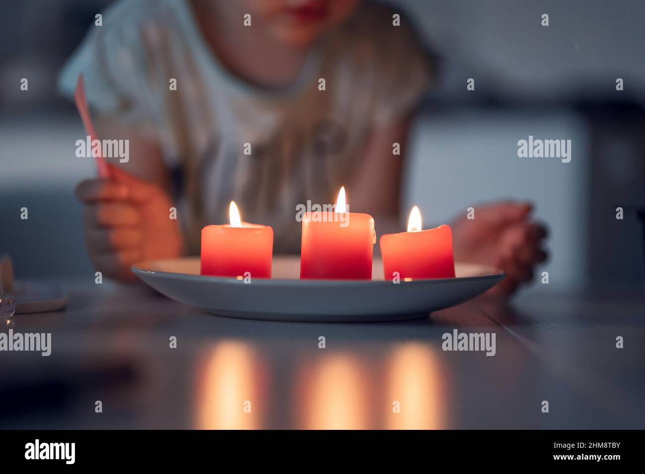 Cute little Girl above three red candles. Little child watching lights ...