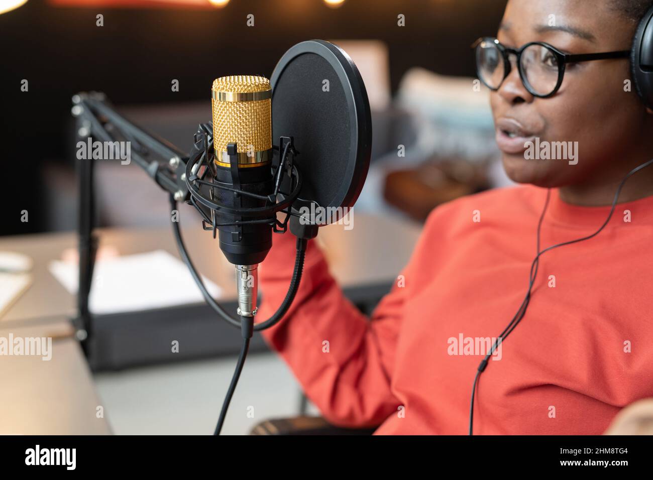 African woman in headphones speaking or singing to the microphone ...