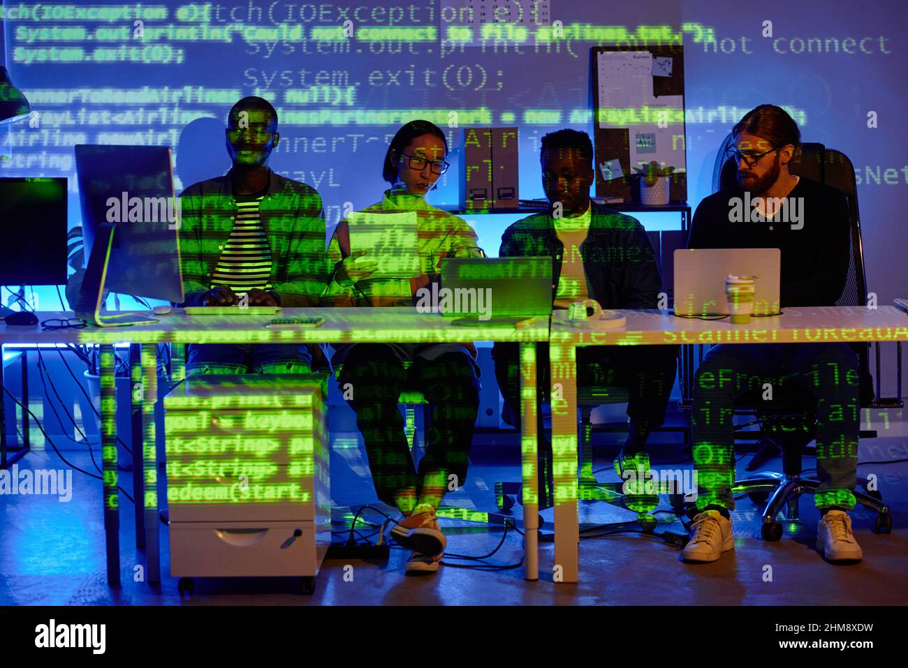 Row of four young intercultural diversity programmers sitting by desk ... Row of four young intercultural diversity programmers sitting by desk ...