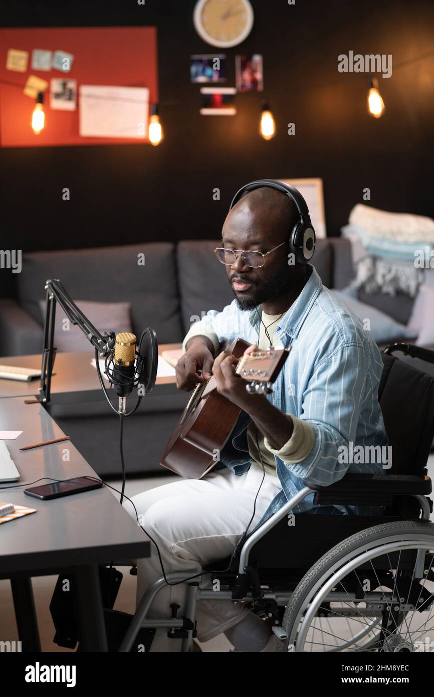 African man with disability playing guitar and singing song while ...