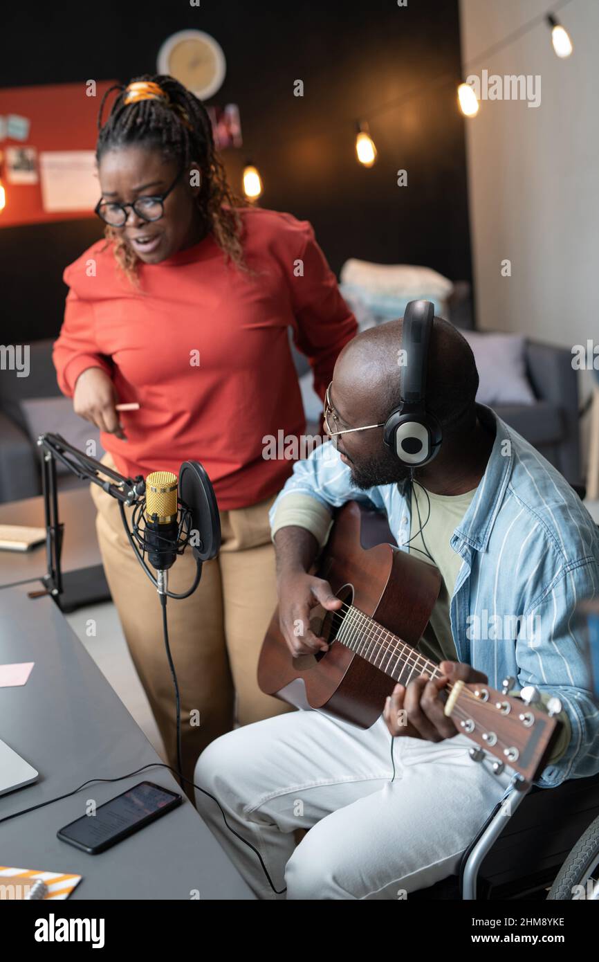 African young woman singing song while her friend playing guitar ...